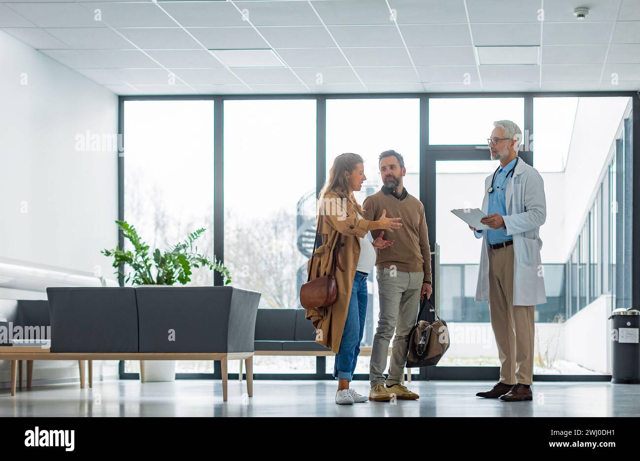 Pregnant woman and husband talking to obstetrician in hospital ...