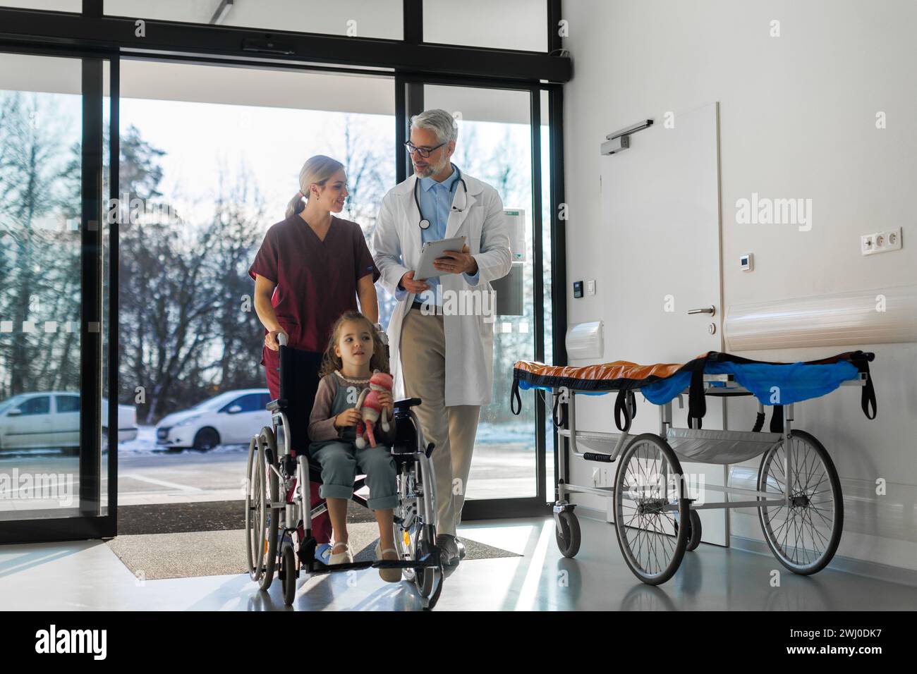 Friendly pediatrician nurse talking, pushing little patient in ...