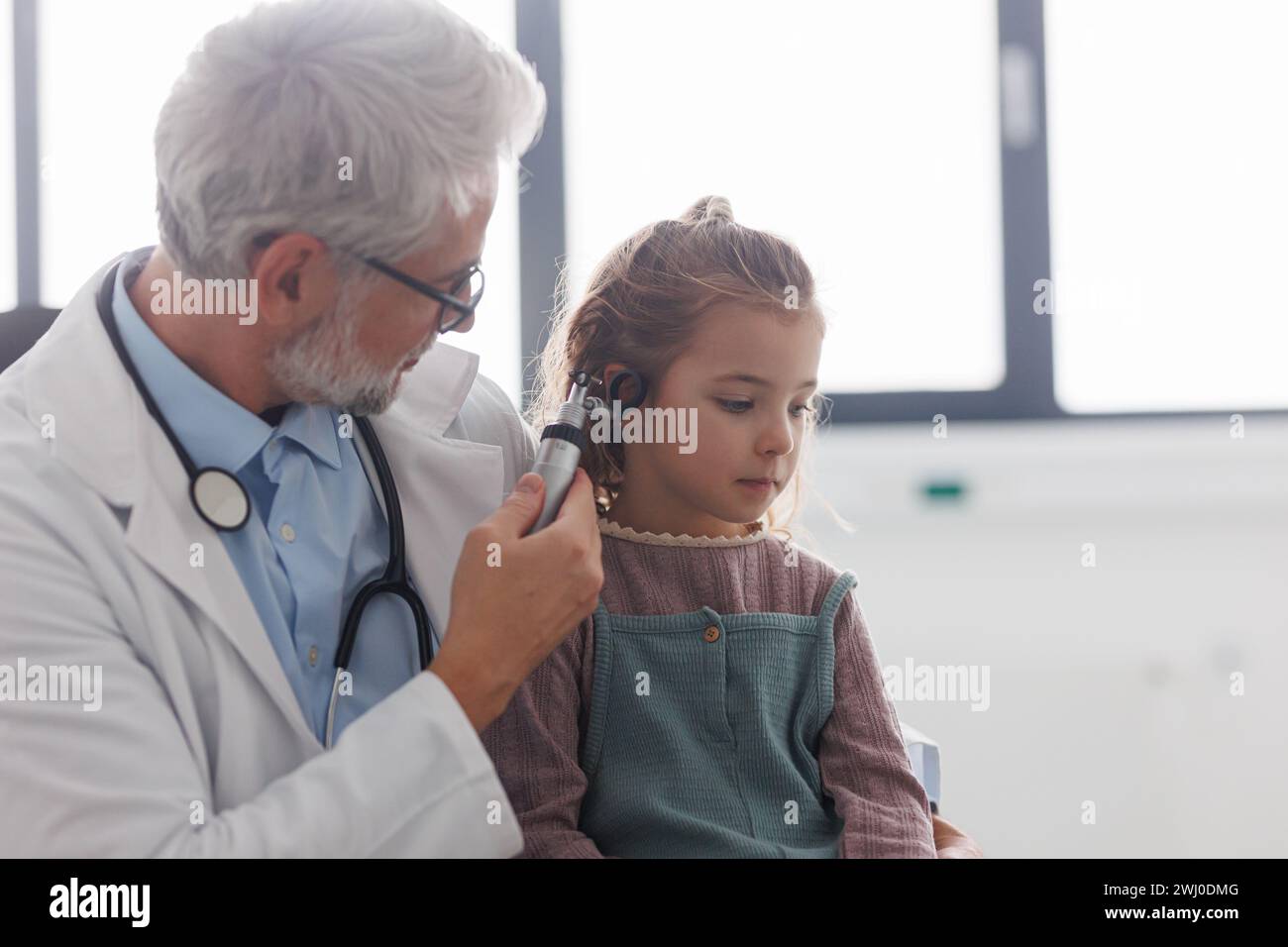 Doctor examining little girl's ear using otoscope, looking for ...