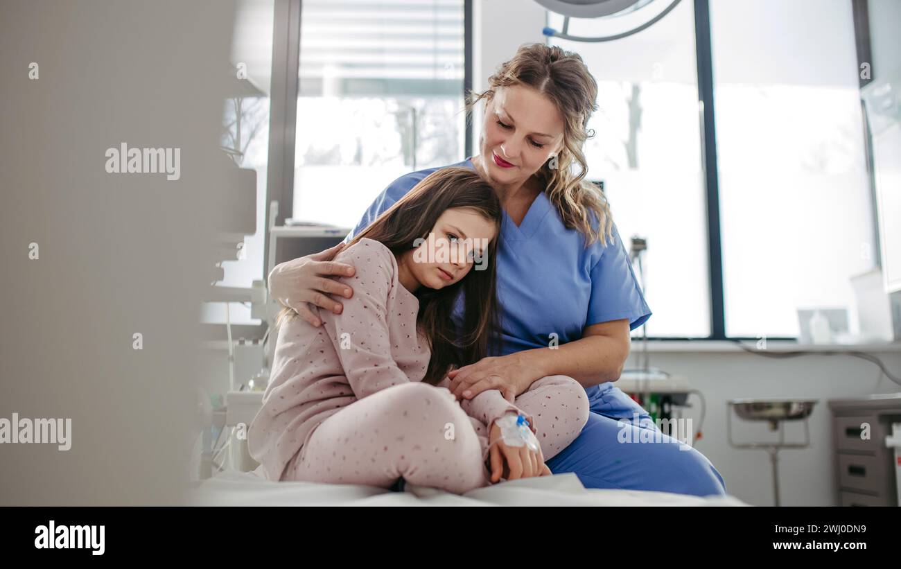 Supportive doctor soothing a worried children patient in emergency room ...