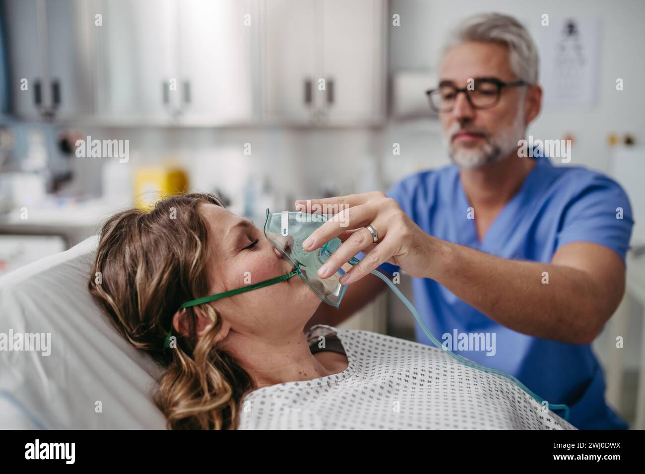 Doctor putting oxygen mask on patient face. Male nurse taking care of ...