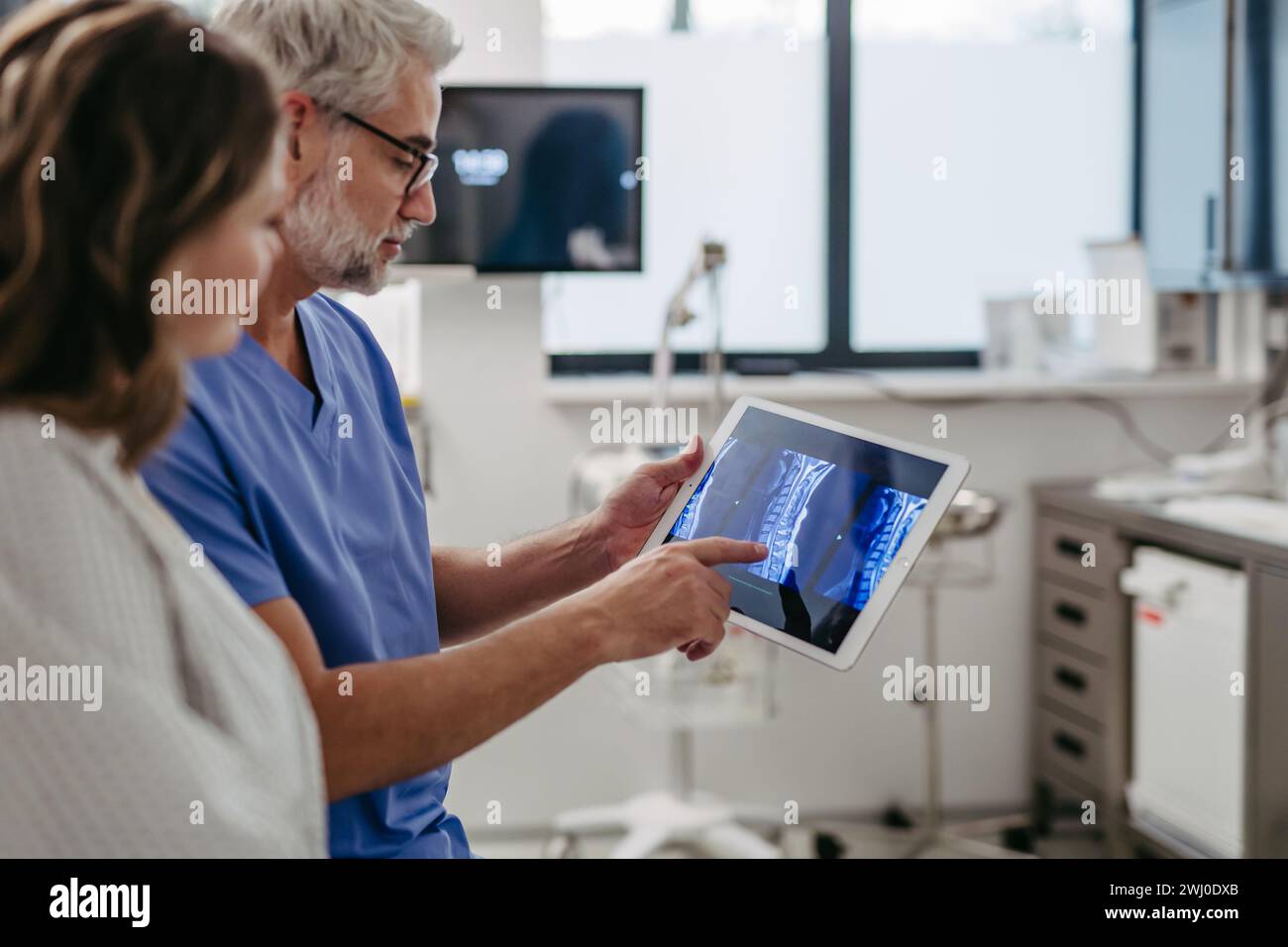 Doctor showing female patient MRI scan on tablet, discussing test ...
