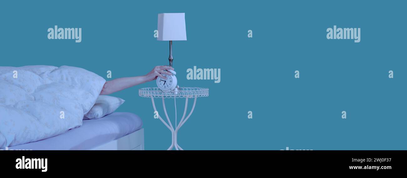 Female arm on the bed turns off the alarm clock wake up. Putting alarm ...