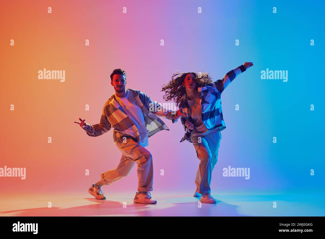 Dancing couple moves in sync, man and woman, dancing in neon-lit studio ...