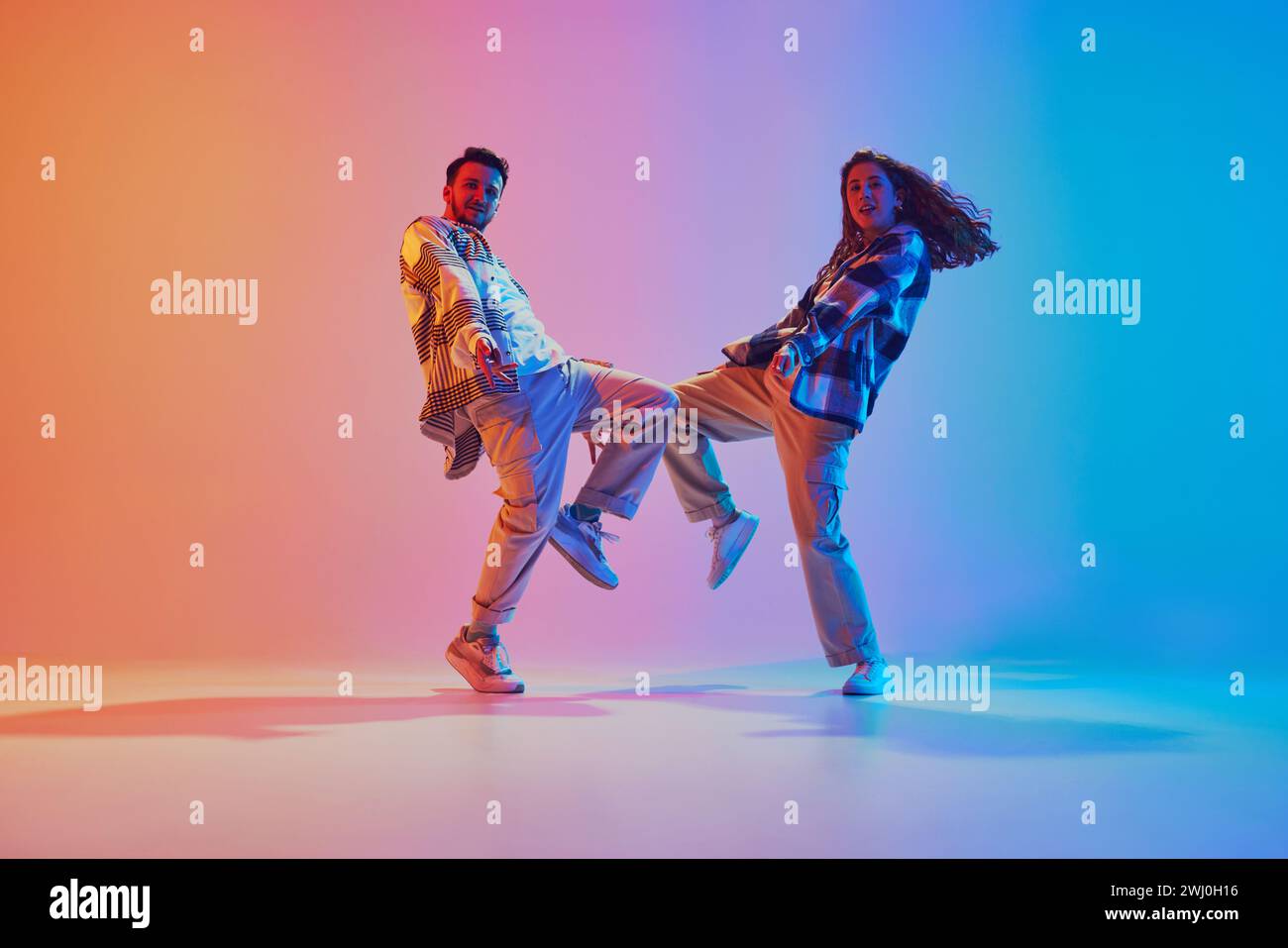 Full-length portrait of dancers connect mid-step in motion in vivid ...