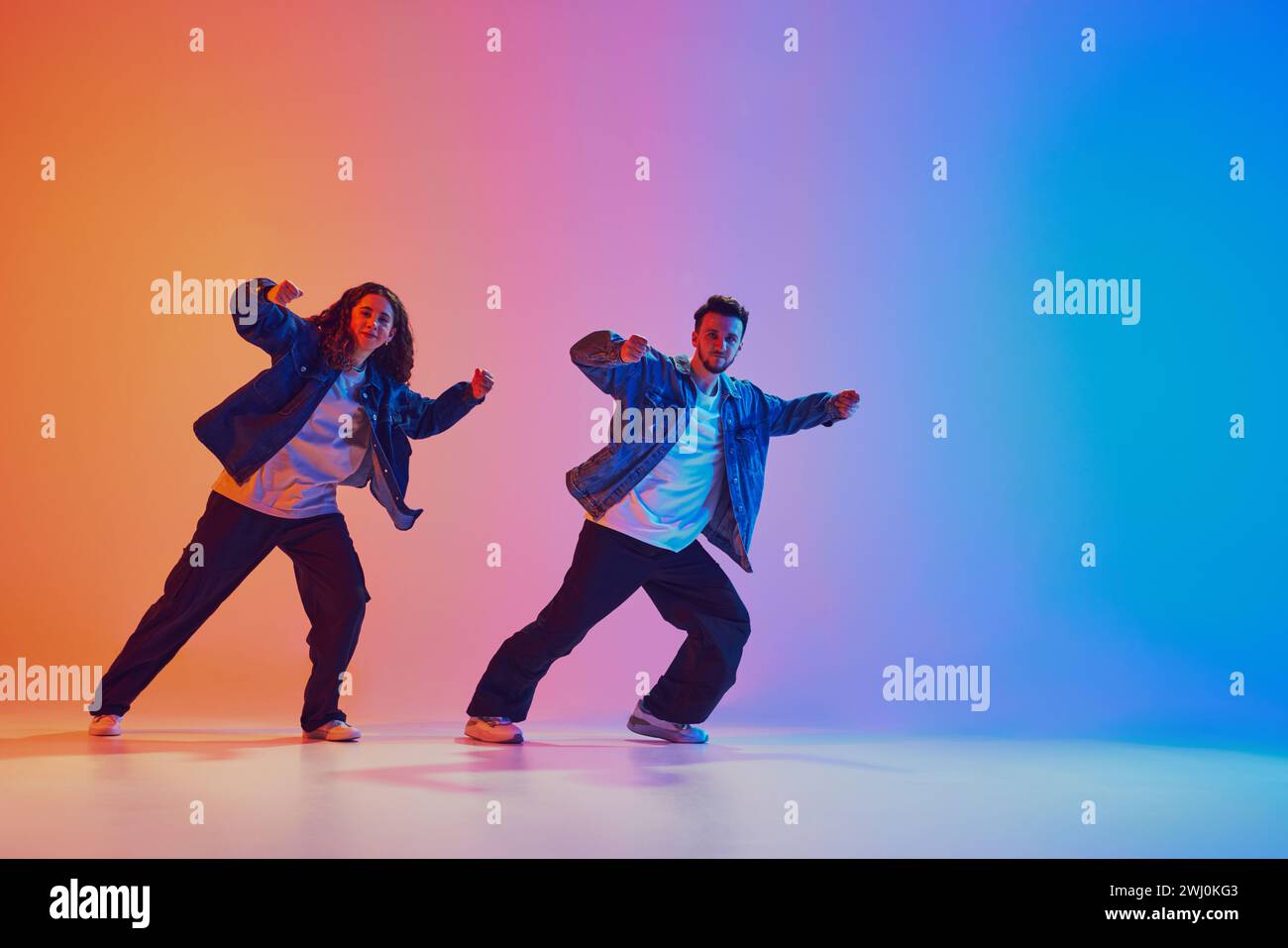 Street style. Two hip-hop dancers, man and woman, in motion against ...