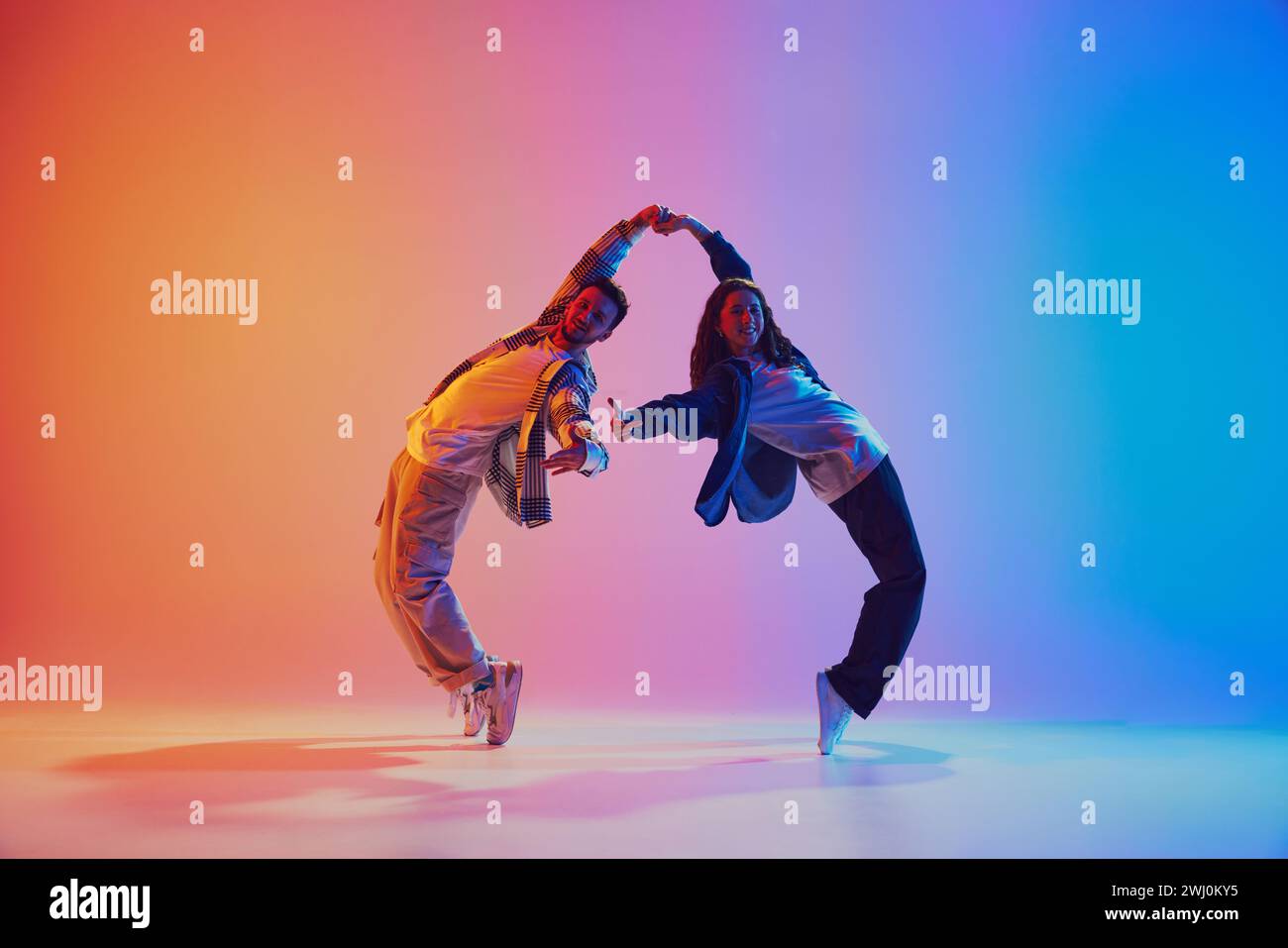 Dynamic shot of young dance duo holding hands while dancing in motion ...
