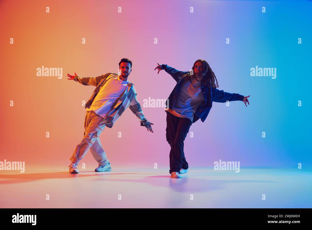 Two dancers, man and woman dancing in motion against gradient studio ...