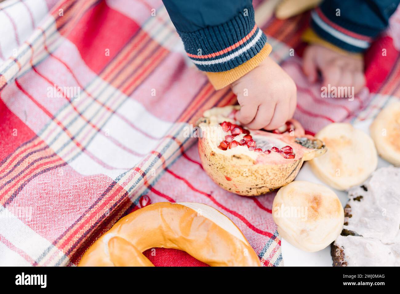Small child picks out seeds from a pomegranate while sitting on a ...