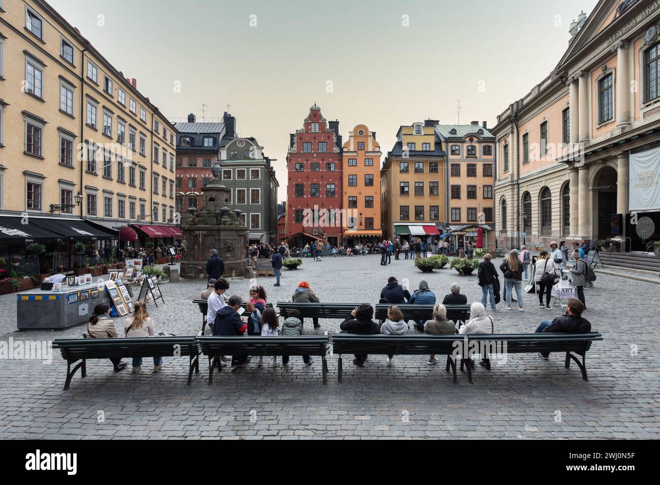A street scene with people sitting on benches in front of colorful ...