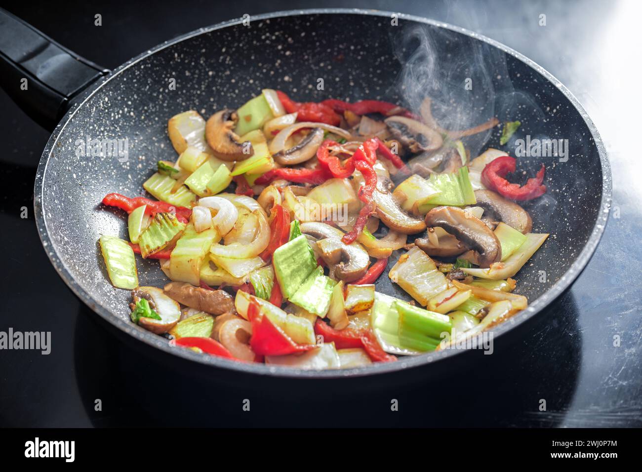 Steaming vegetables are stir-fried in a frying pan with healthy ...