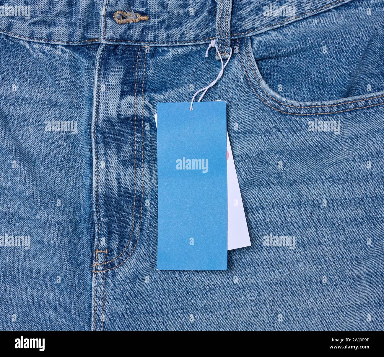Paper price tag on a rope tied to the waistband of blue jeans Stock ...