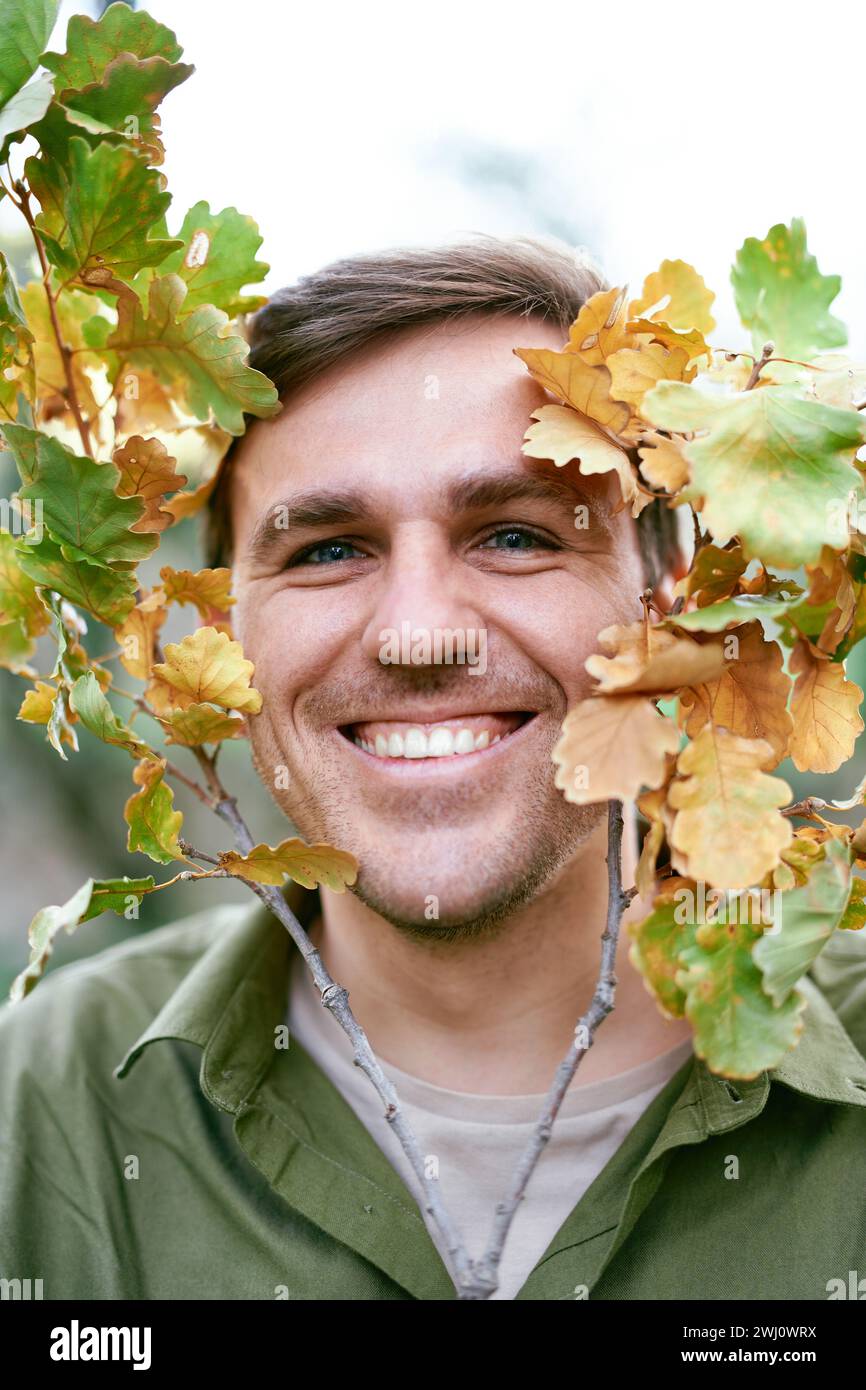 Portrait of a smiling man looking through a yellowed oak branch Stock ...