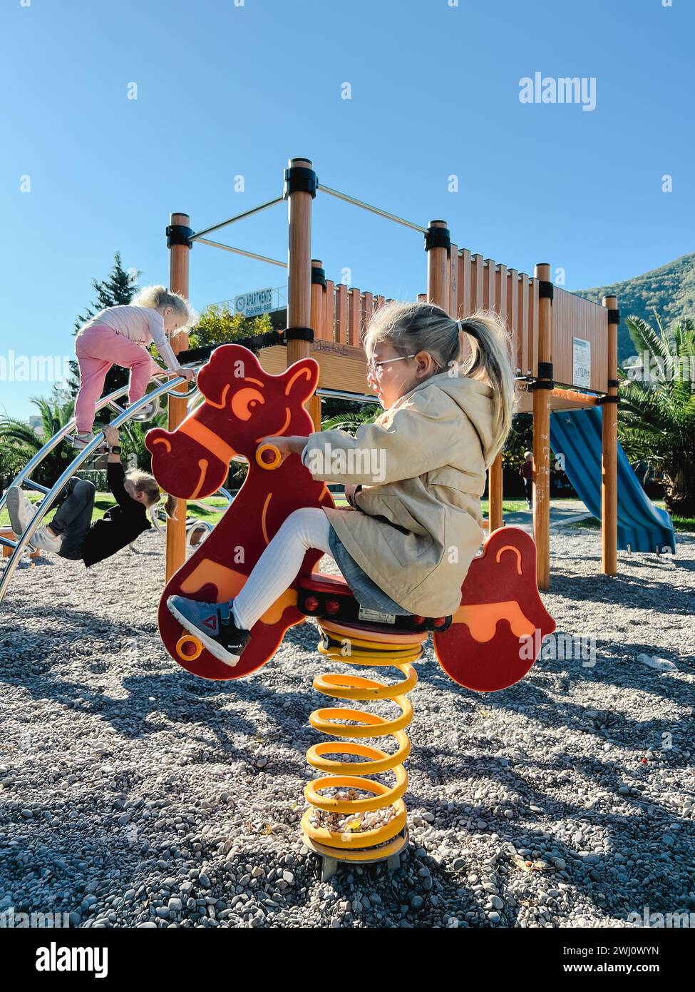 Little girl swings on a swing-spring on the playground Stock Photo - Alamy