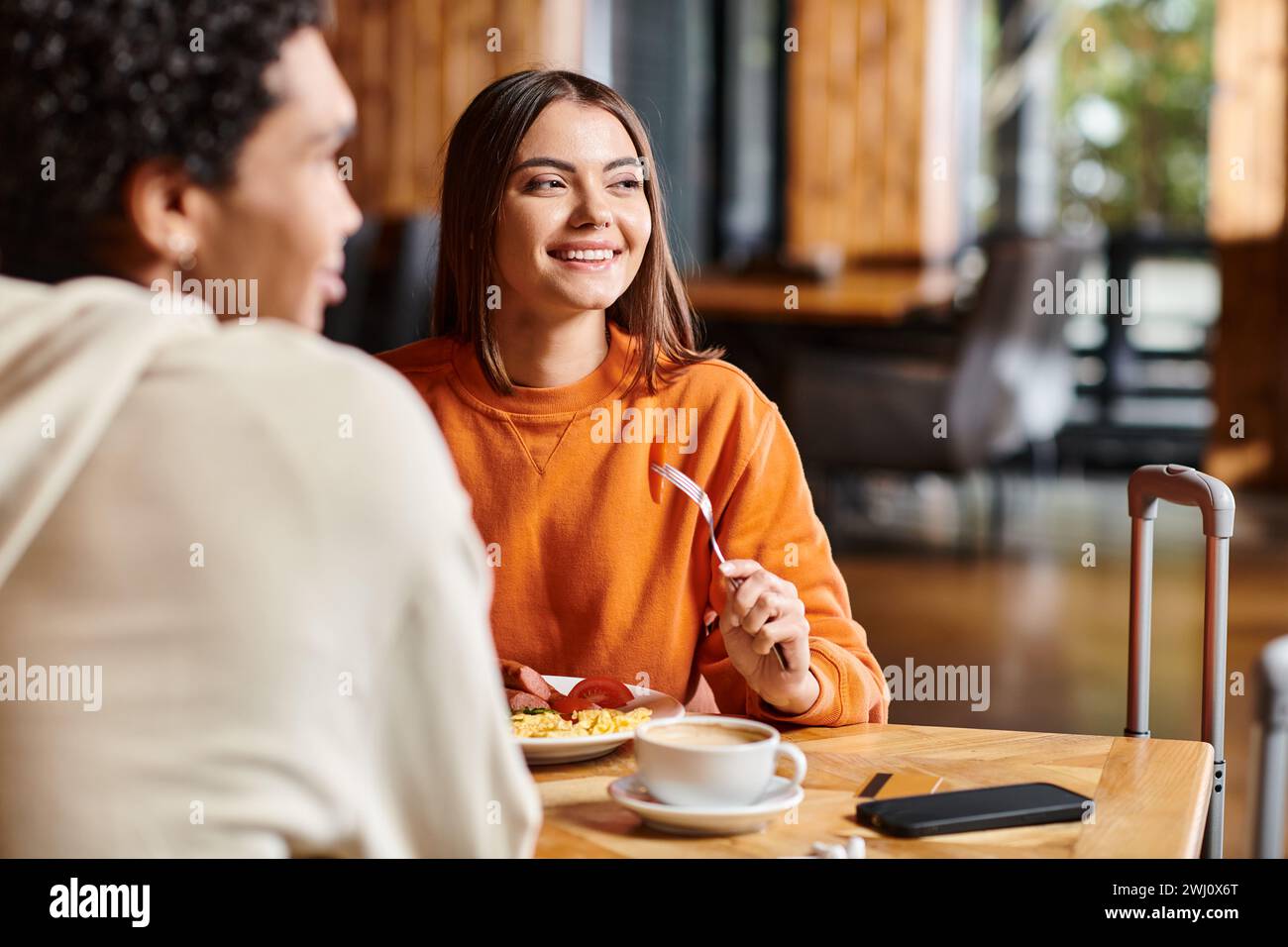 Smiling young woman having a delightful breakfast with boyfriend in a ...