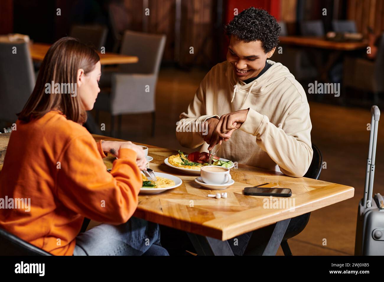 diverse couple shares meal at a restaurant, their faces lit up with joy ...