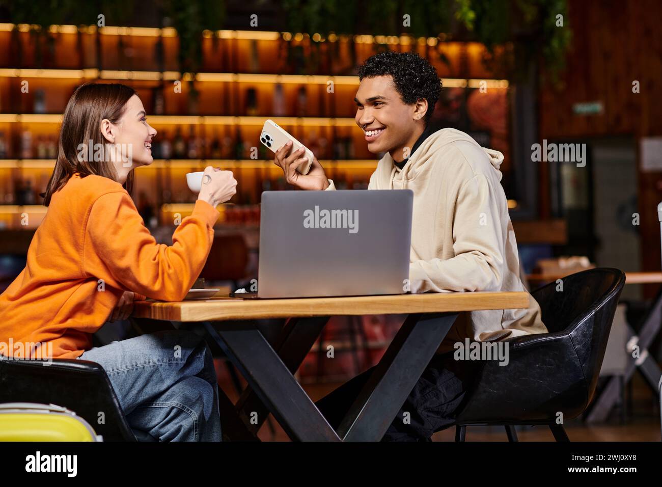 happy diverse couple using a laptop and smartphone in a modern cafe ...
