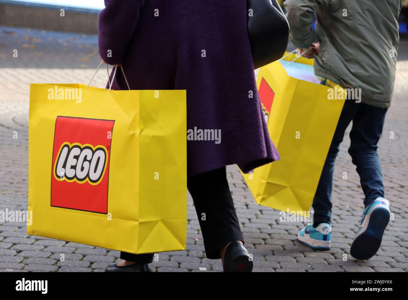 zwei Personen tragen jeweils eine grosse LEGO-Papiertasche, Nordrhein ...