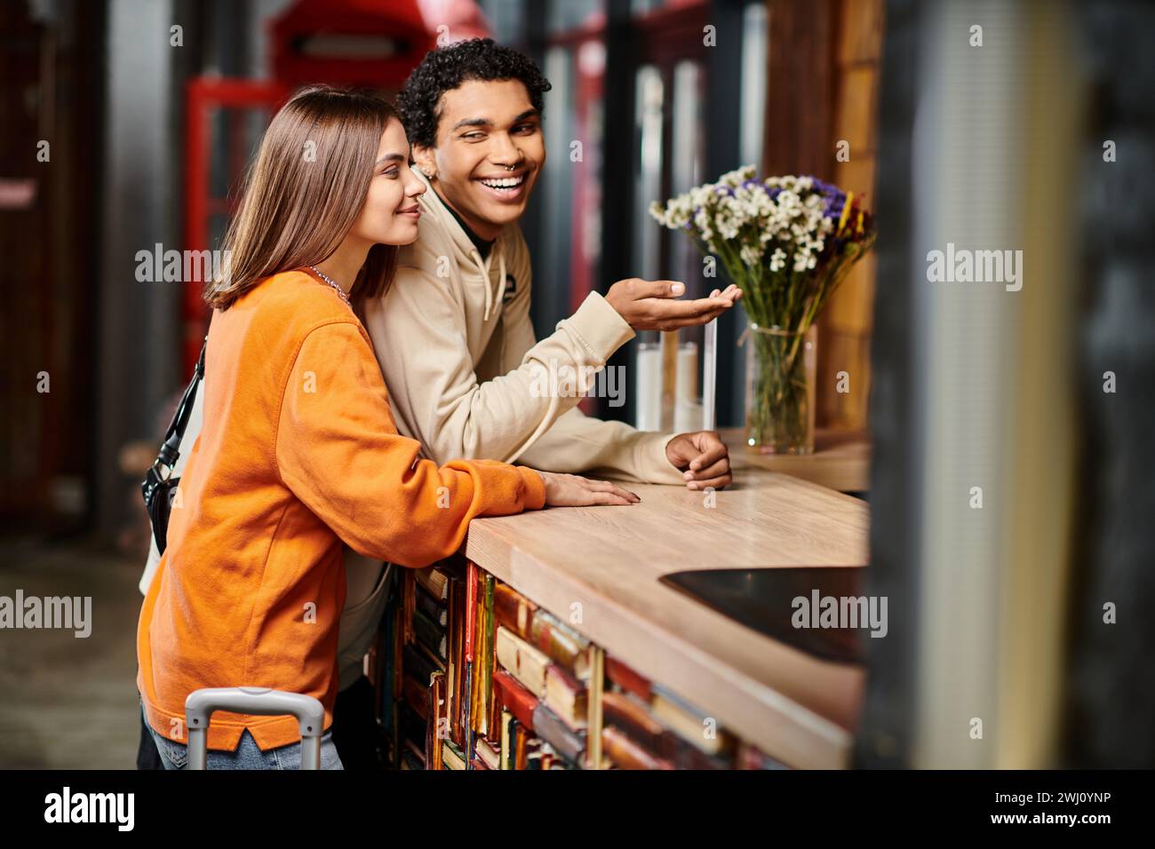 happy young woman smiling near her black boyfriend at hostel reception ...