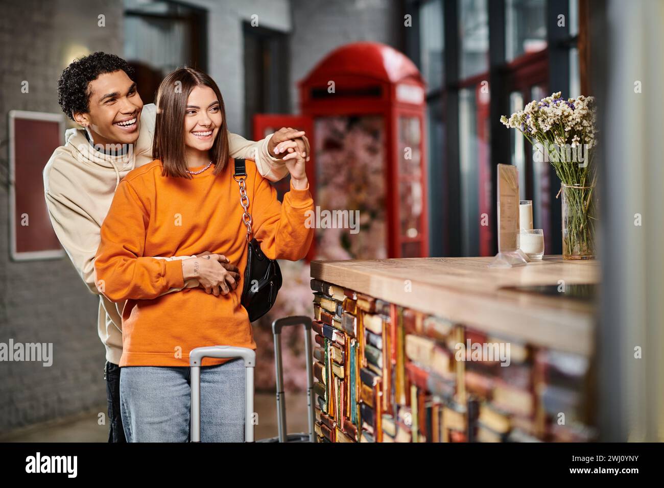 A smiling woman and man stand together at hostel reception desk ...