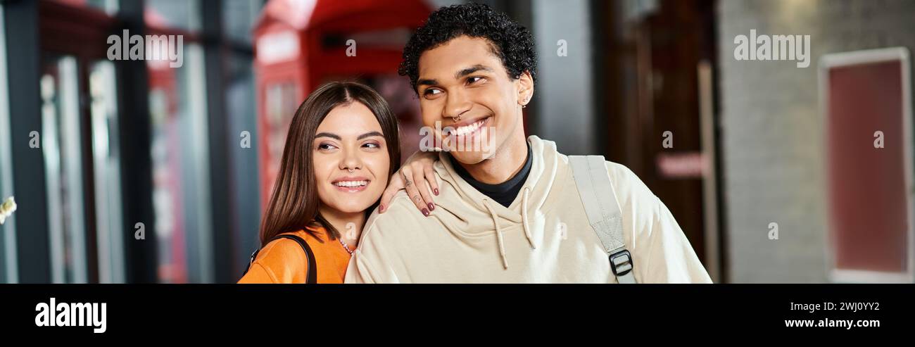Joyous interracial couple smiling inside of hostel, seemingly excited ...