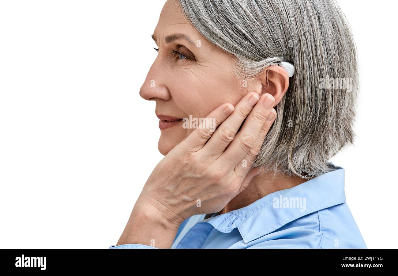 Middle-age woman with hearing impairment using hearing aid, side view ...