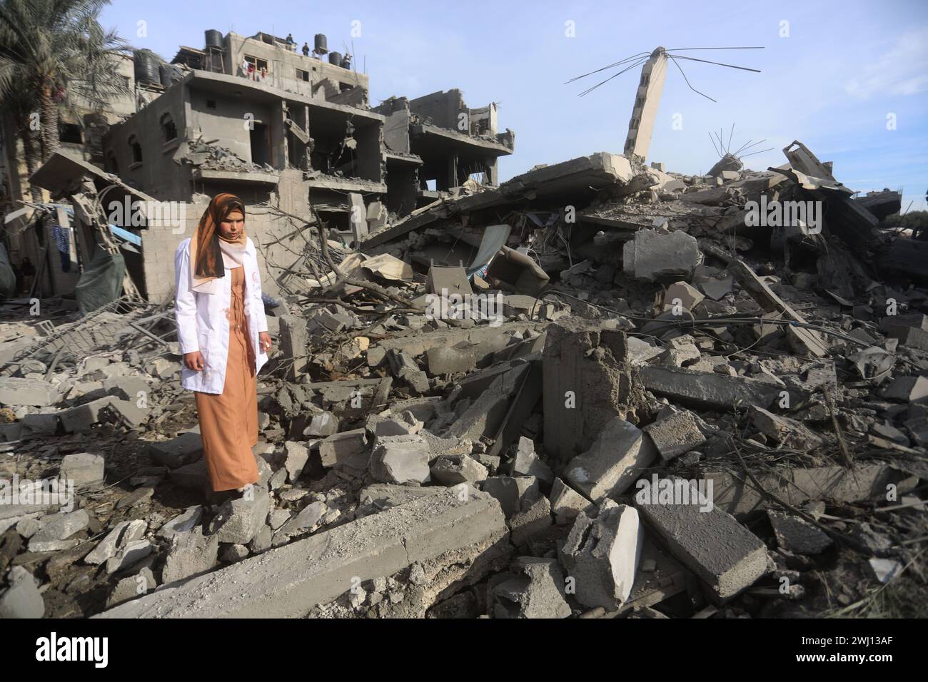 Rafah. 12th Feb, 2024. A woman checks the rubble of buildings damaged ...