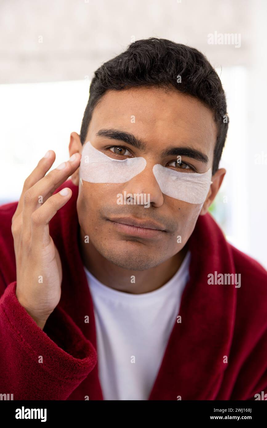 Happy biracial man applying uder-eye patches in bathroom at home Stock ...