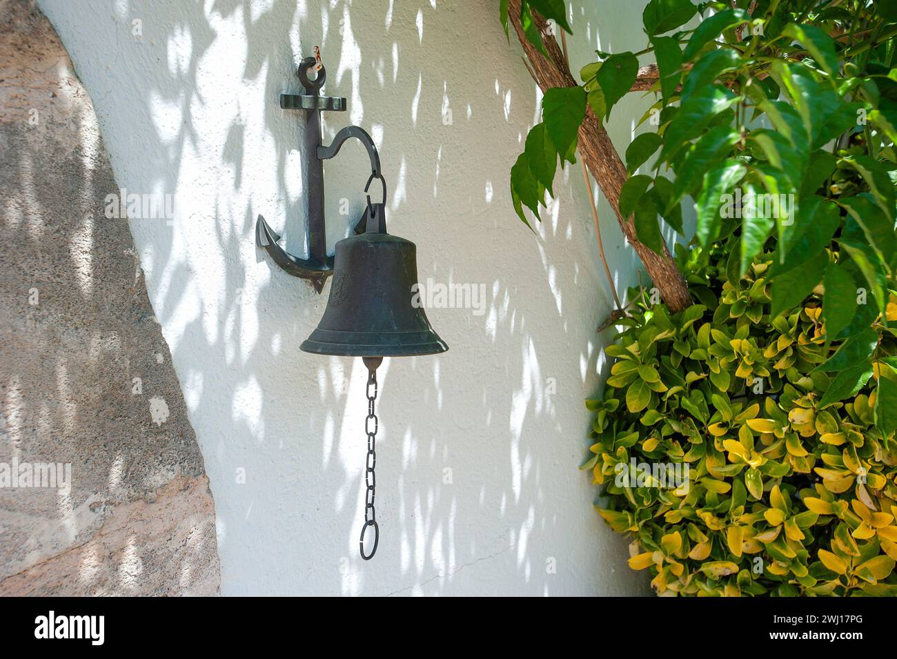 Wall mounted bell with anchor shape, Finca, Spain Stock Photo - Alamy