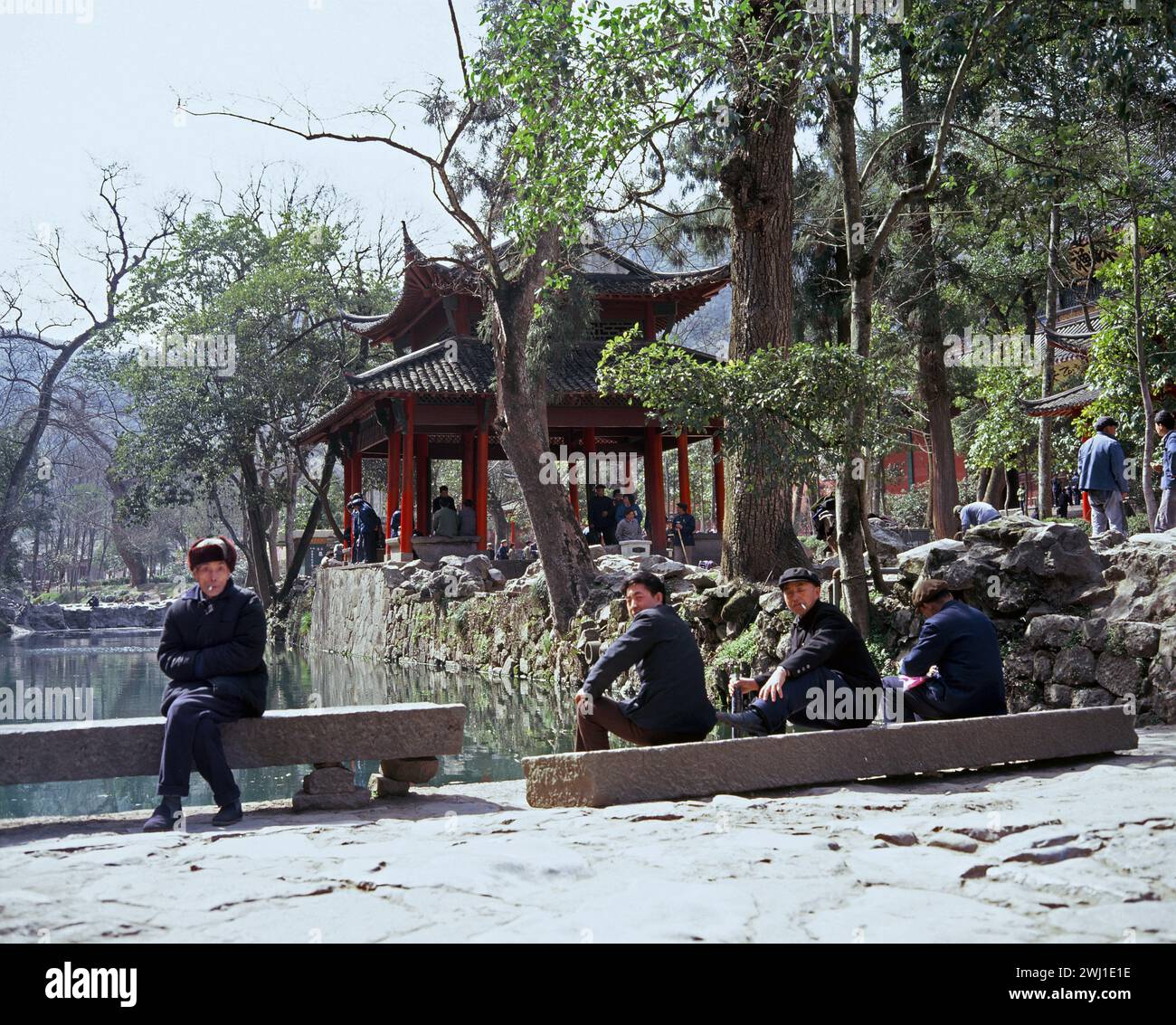 China. Zhejiang. Hangzhou. Lingyin Temple. Local men sitting by garden ...