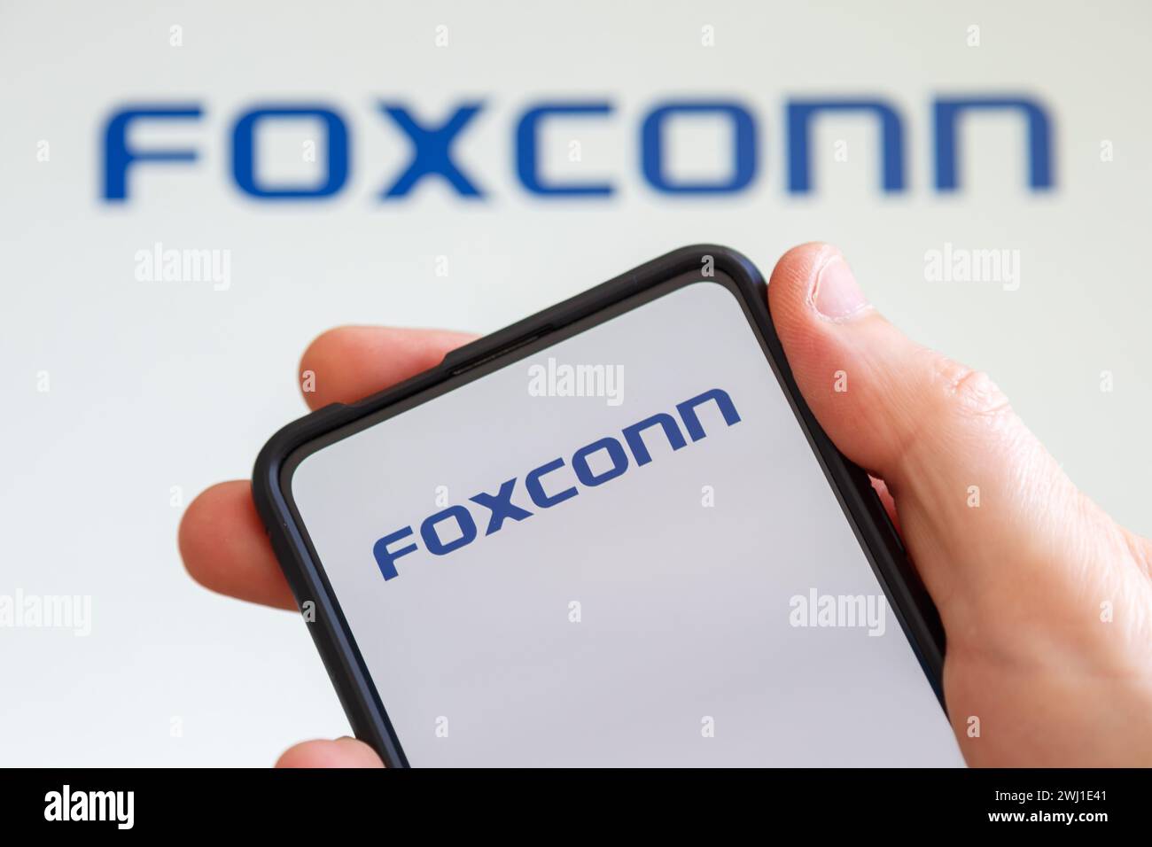 Hand holding cell phone with Foxconn logo of computer manufacturer ...