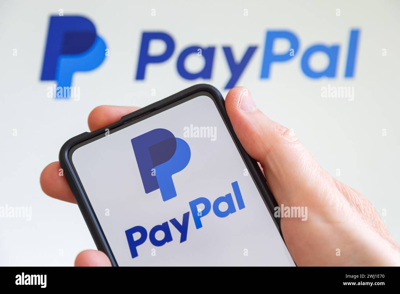 Hand holding cell phone with PayPal logo of online payment provider ...