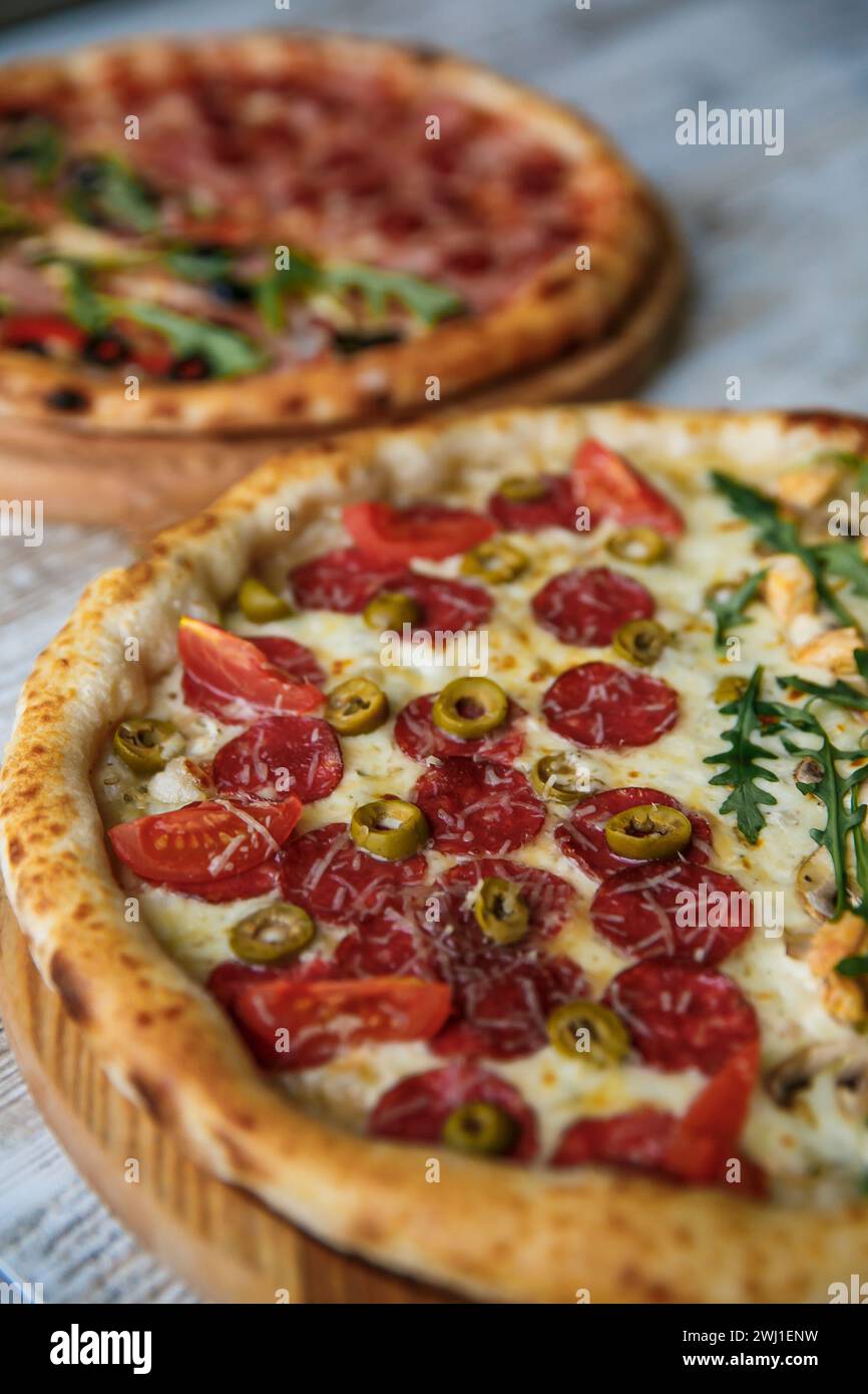 Two tasty different pizzas with variety of toppings and cheese on ...