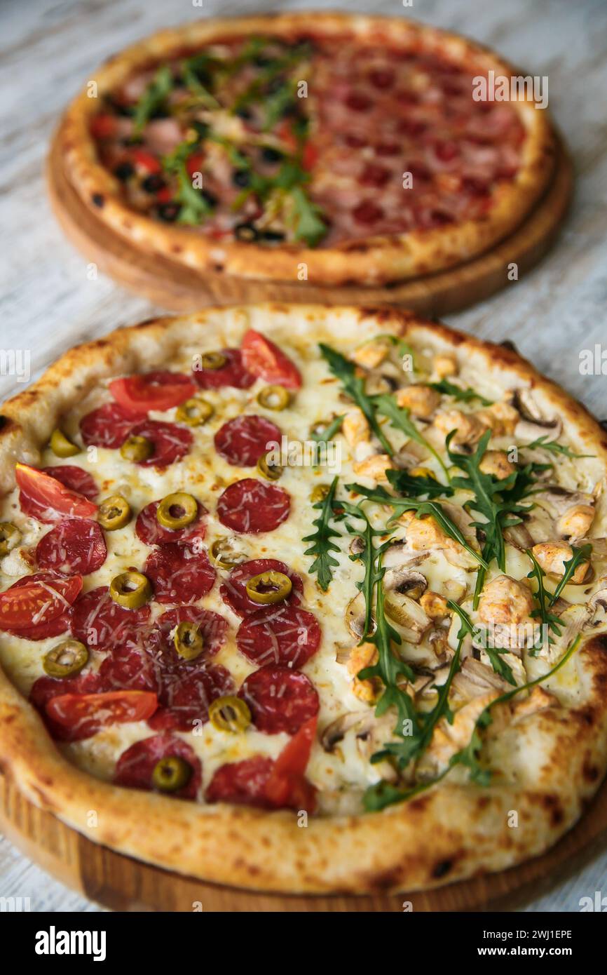 Two tasty different pizzas with variety of toppings and cheese on ...