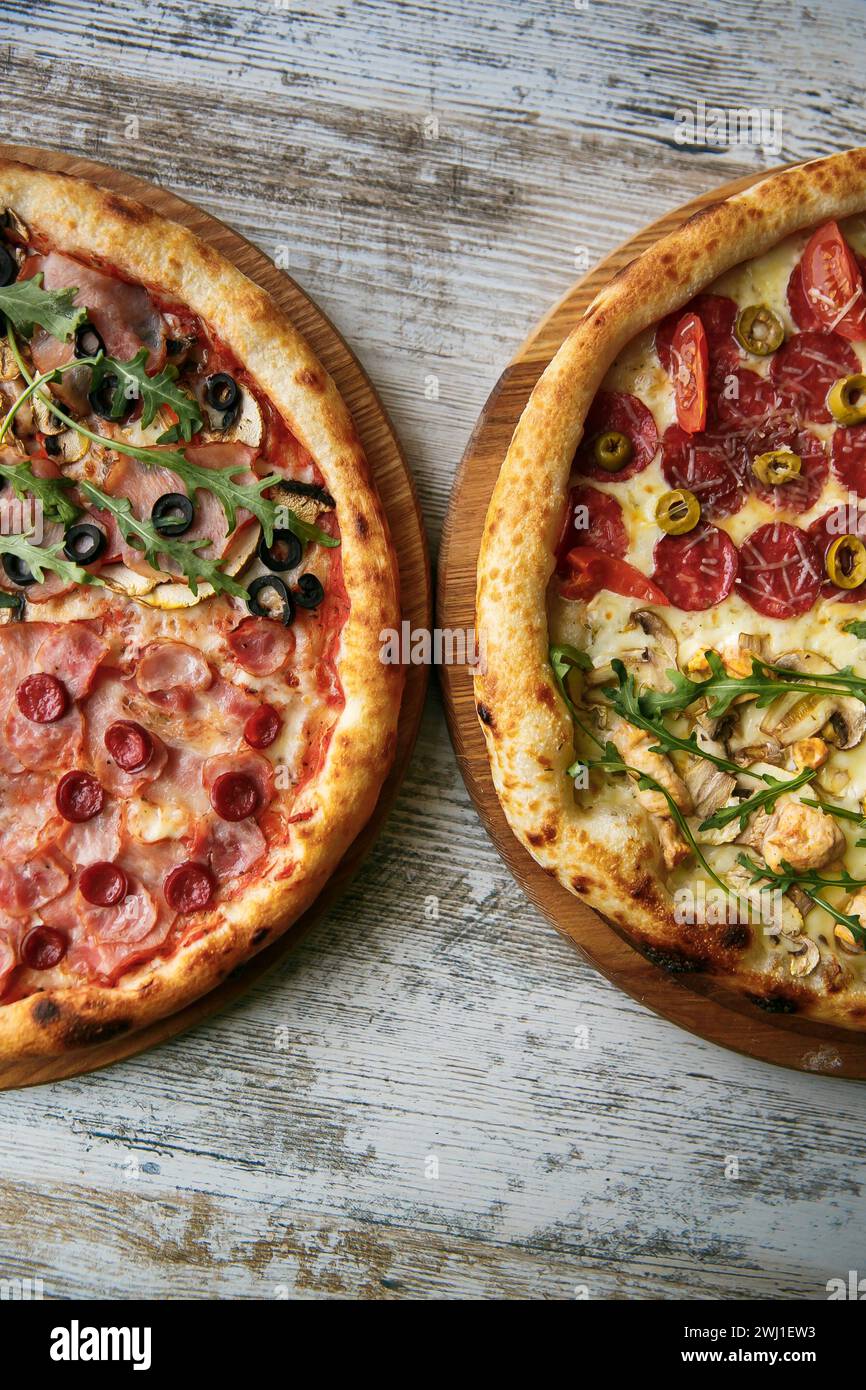 Two tasty different pizzas with variety of toppings and cheese on ...