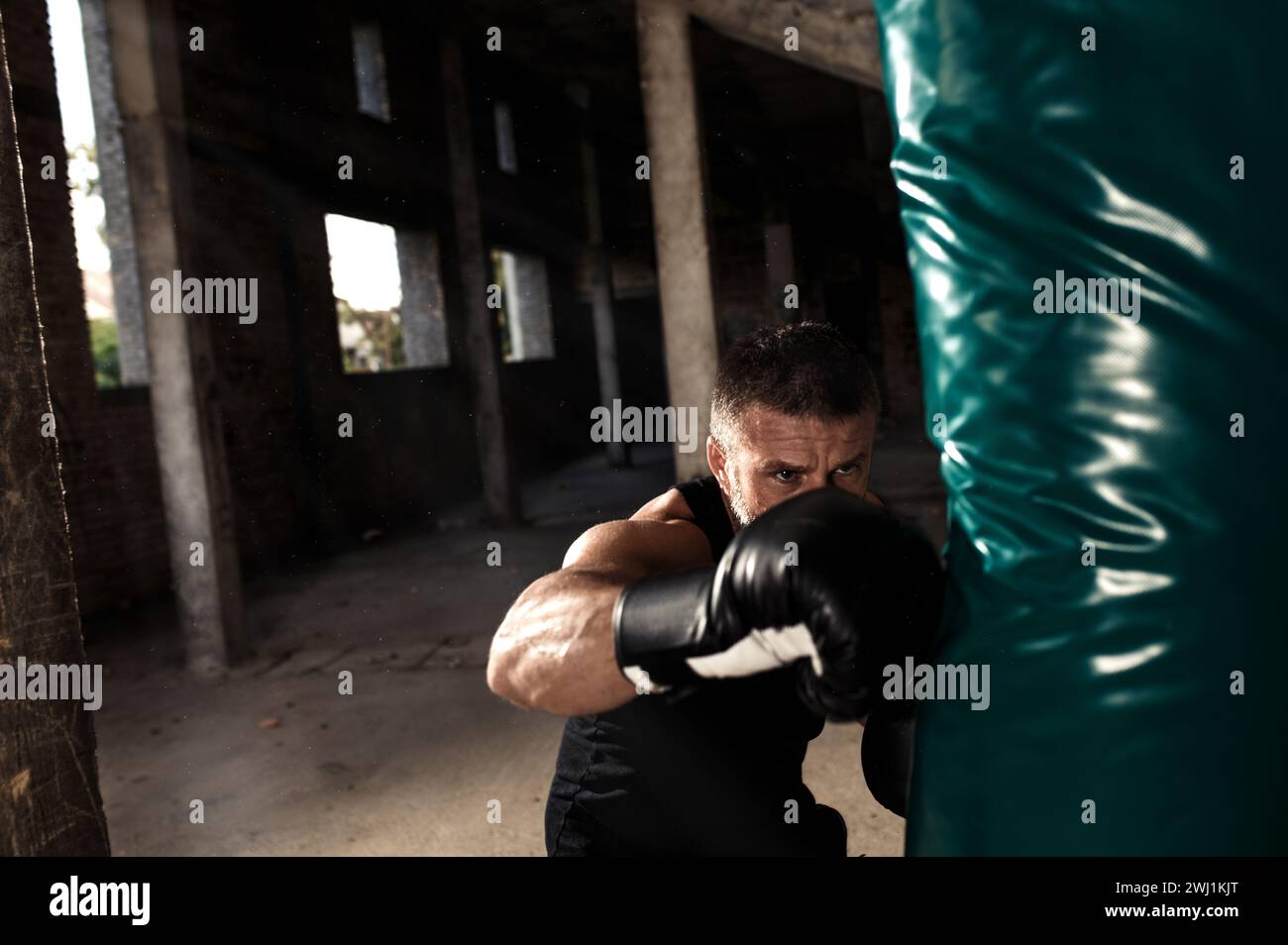Male boxer punching a boxing bag in warehouse Stock Photo - Alamy