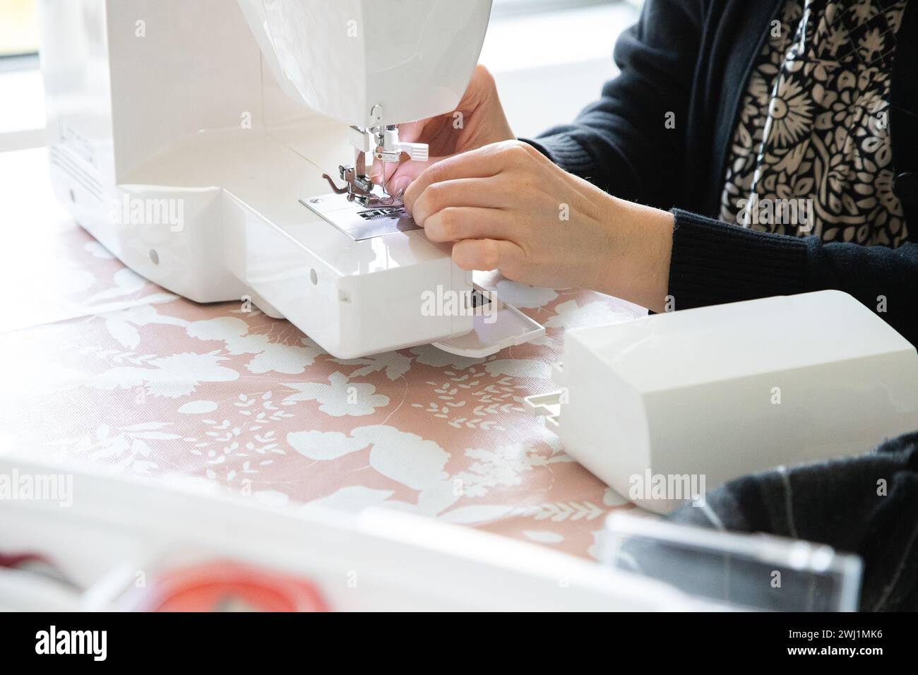 Woman's hand in front of the sewing machine to thread the needle and ...