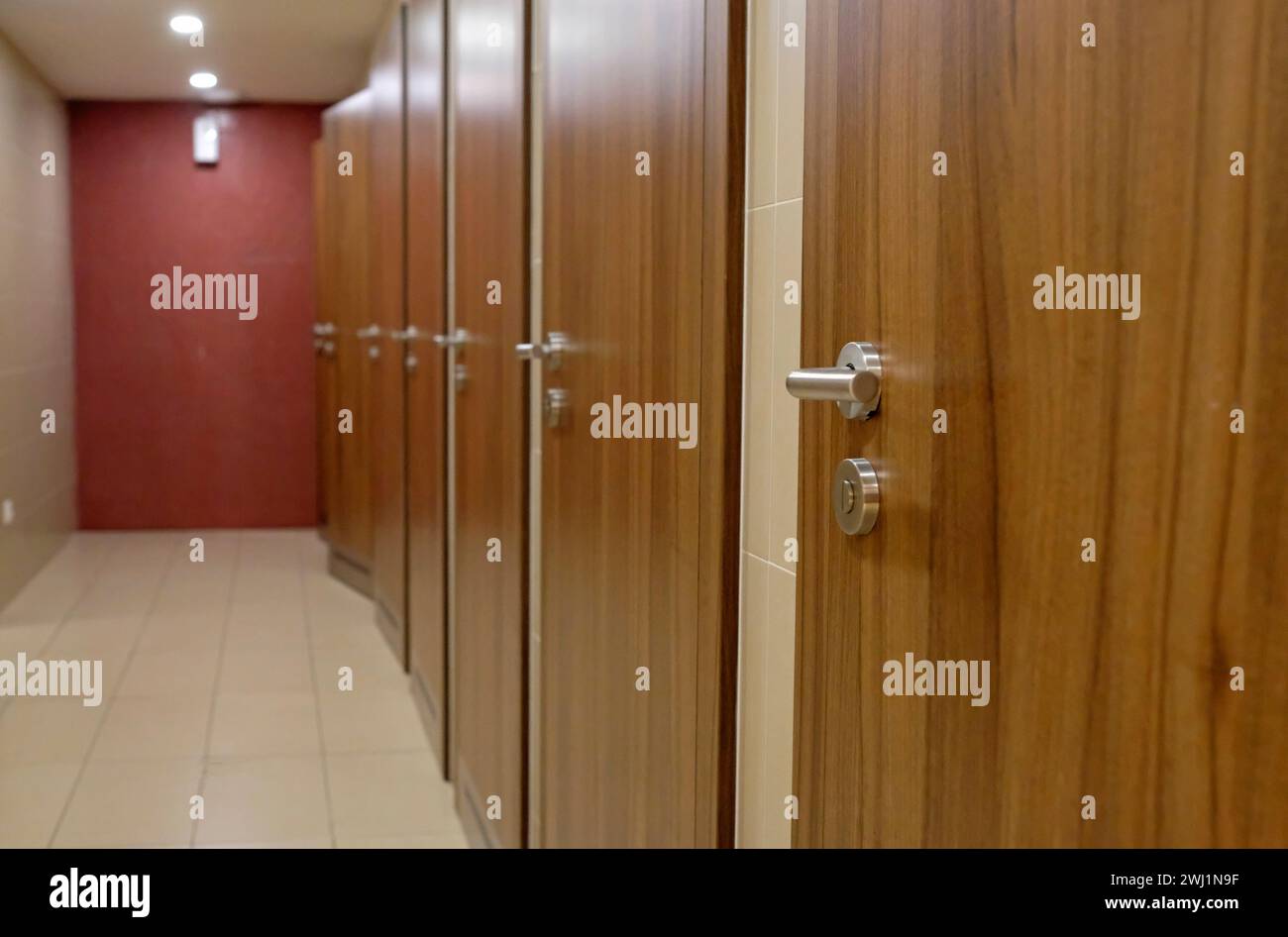 Multiple stalls with wooden doors in a row in a bathroom Stock Photo ...