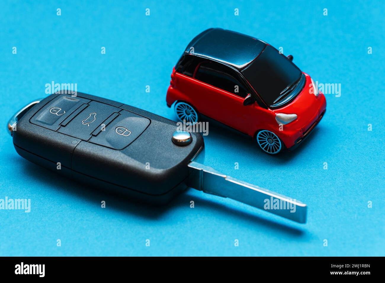 Extended car key and red toy car on blue background Stock Photo - Alamy