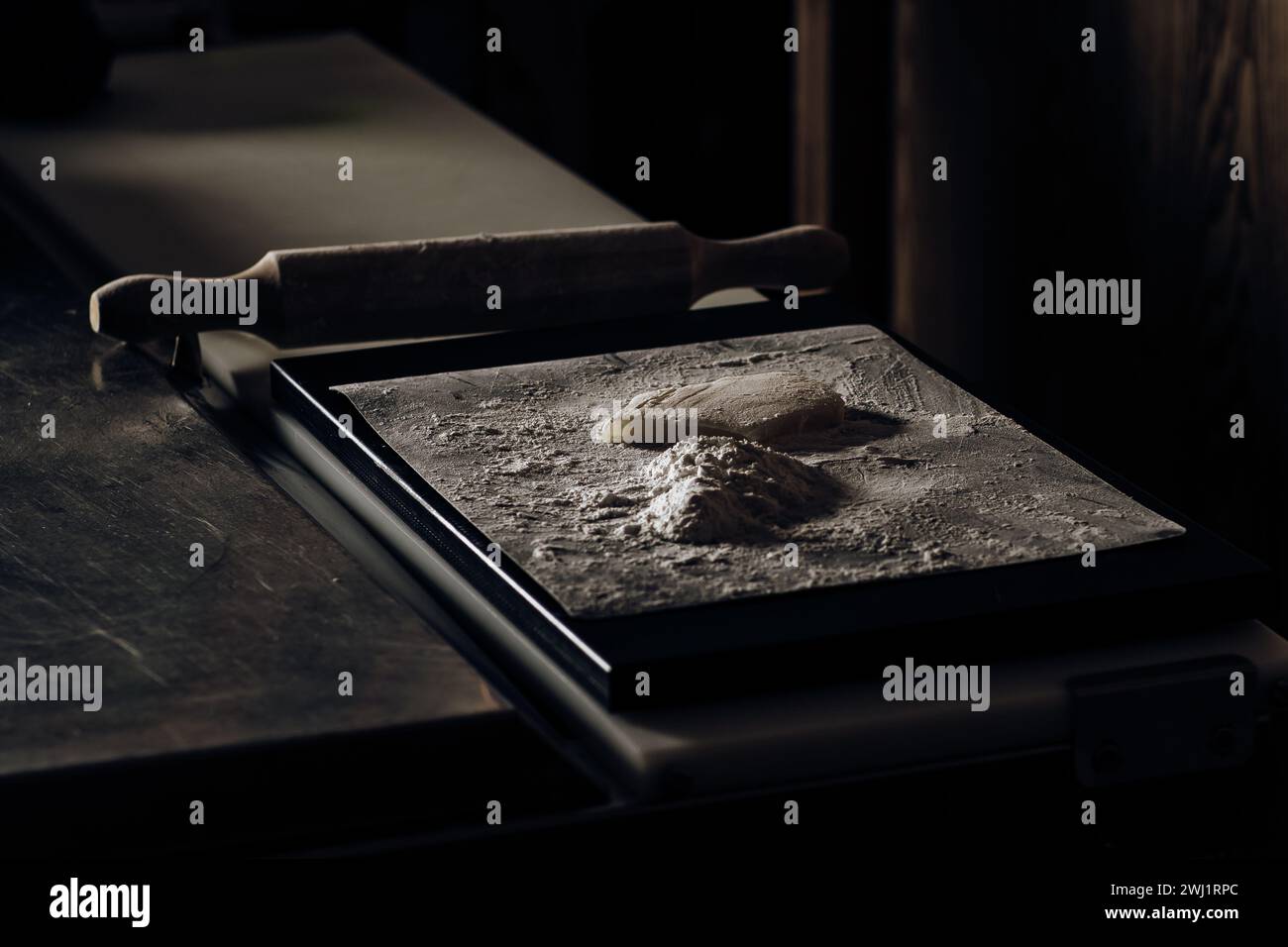 Restaurant kitchen table with a flour-filled tray, dough sprinkled with ...