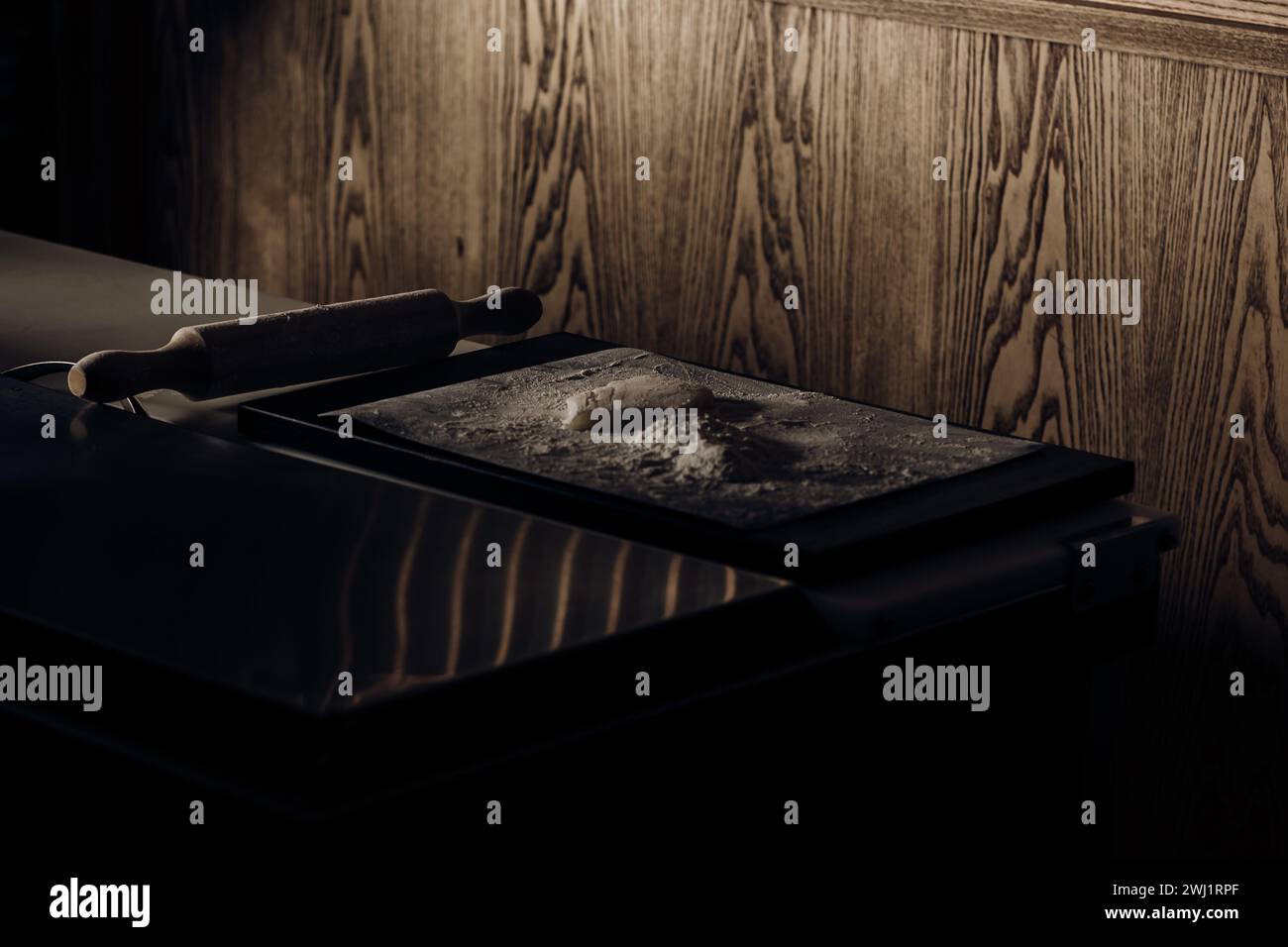 Restaurant kitchen table with a flour-filled tray, dough sprinkled with ...