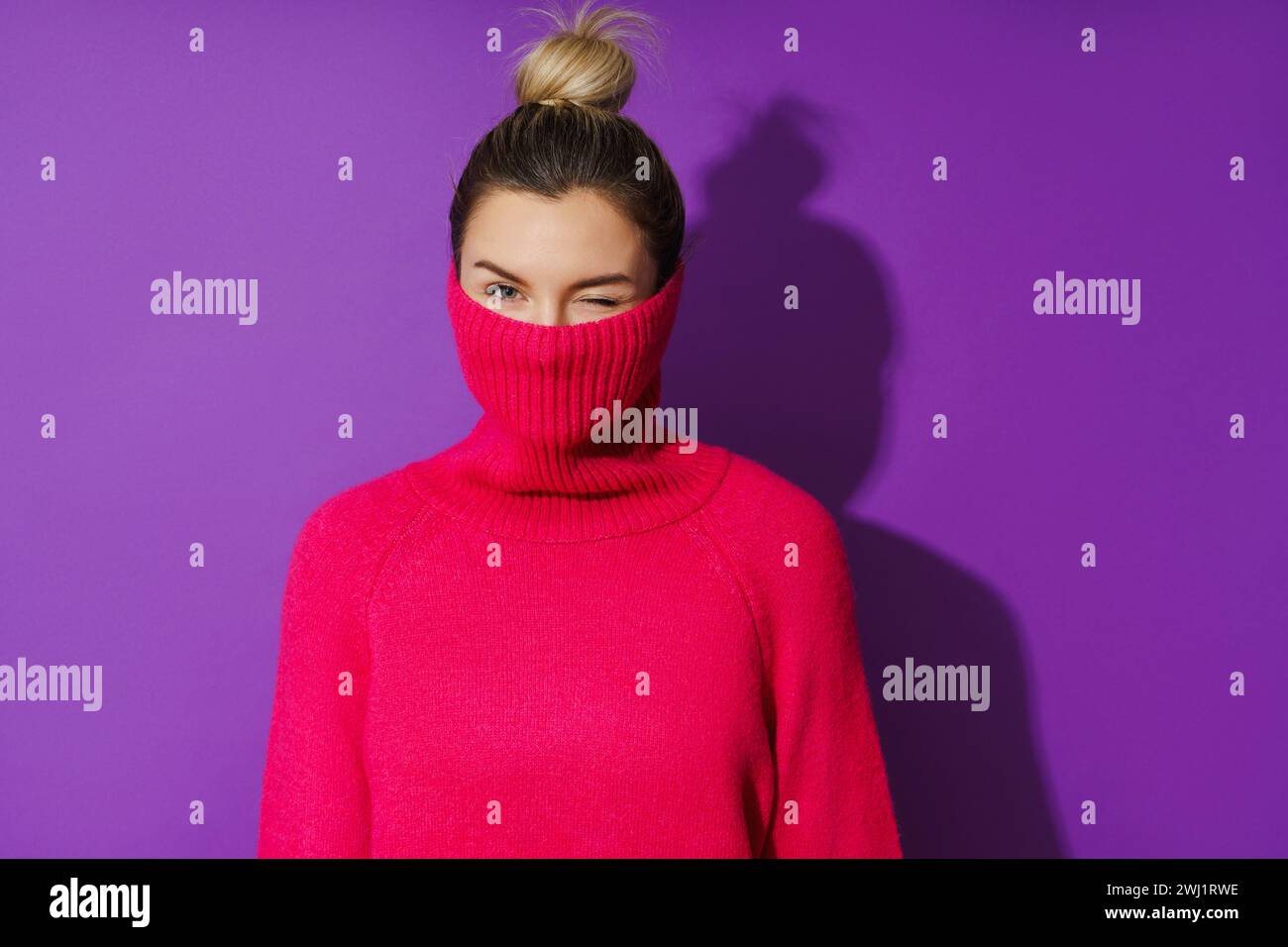 Young woman is hiding her face inside a warm and cozy polo neck sweater ...