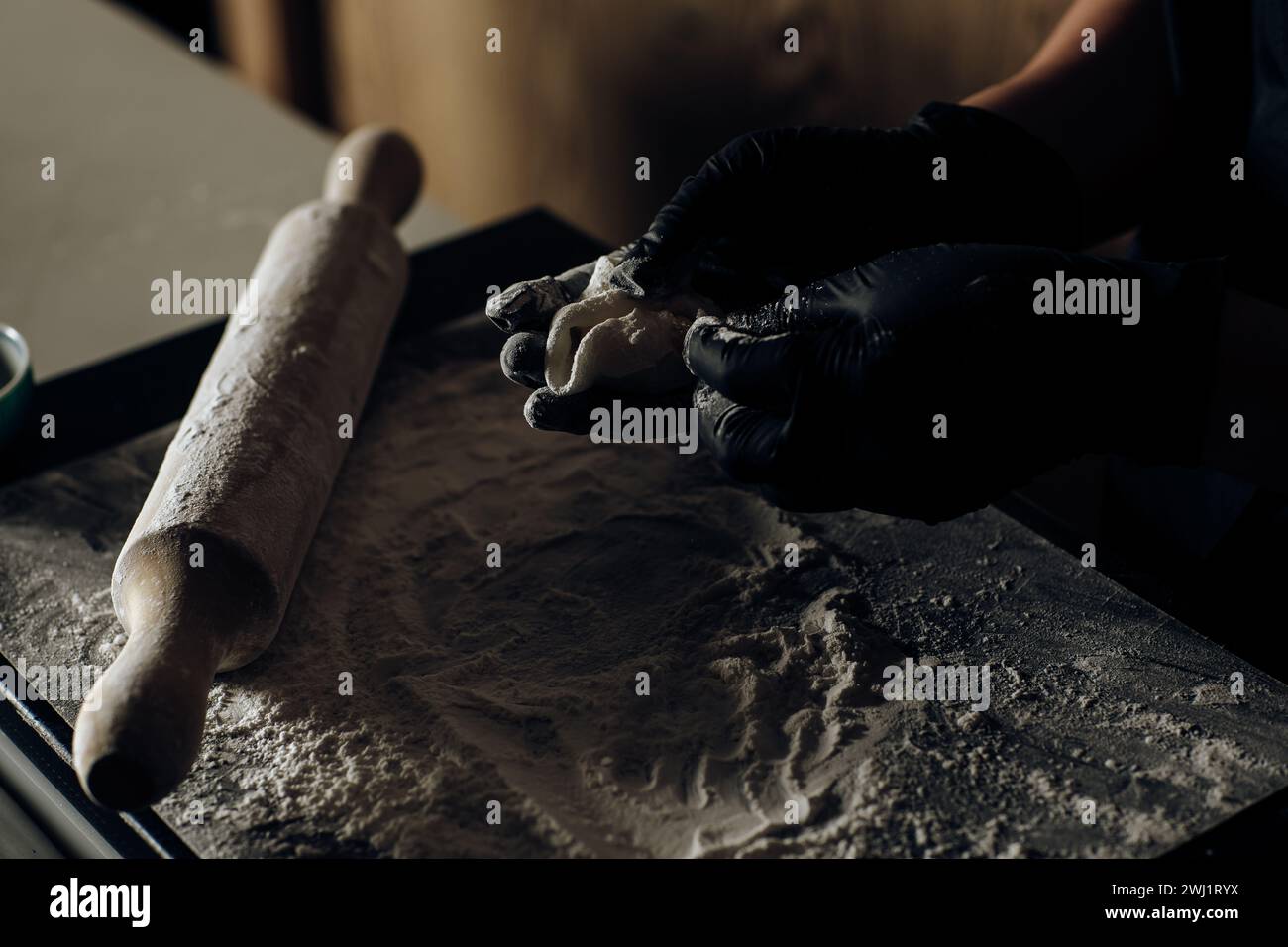 Hand in black gloves delicately shaping dough, showcasing meticulous ...