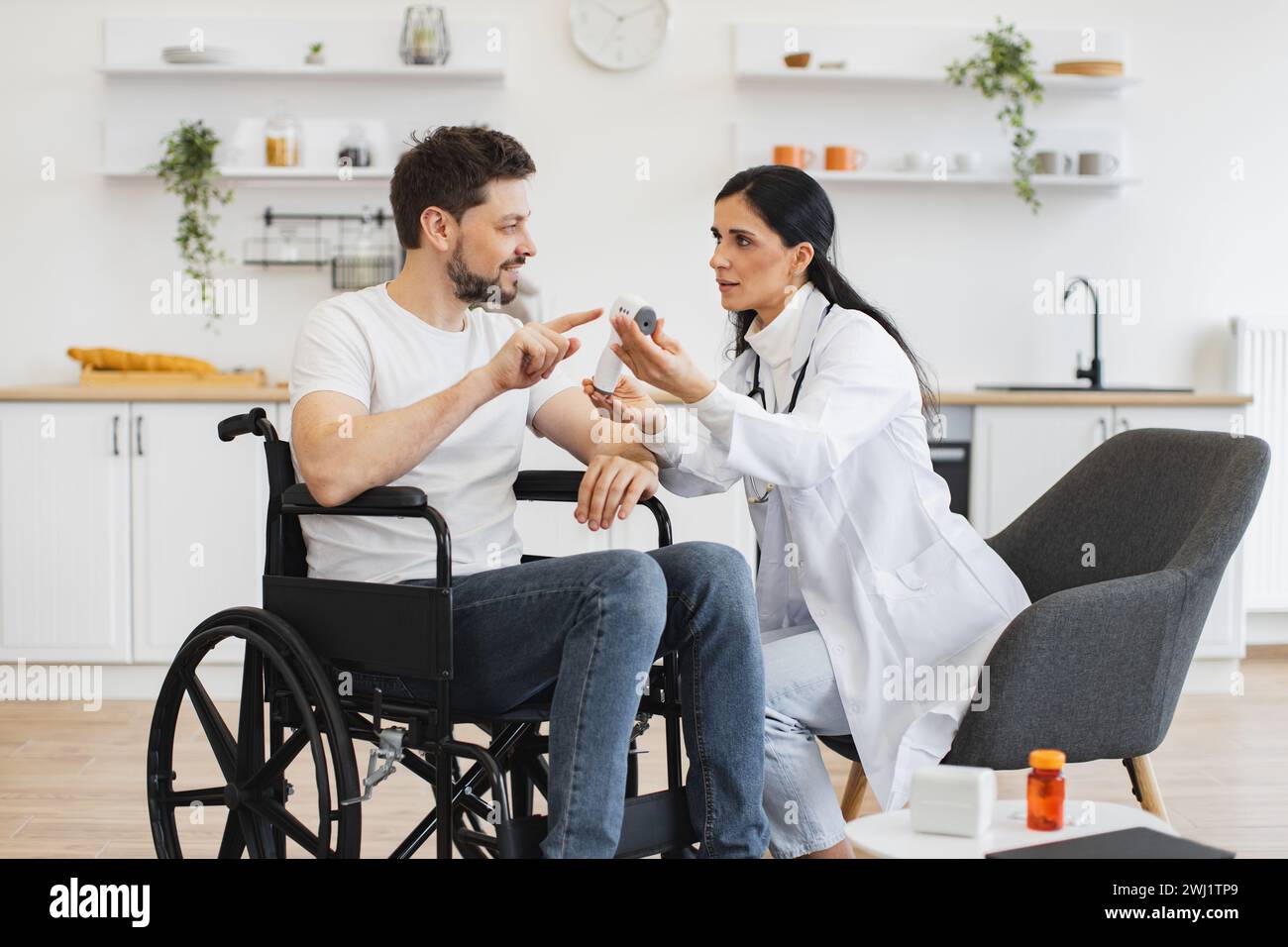 Woman doctor or nurse, visiting her mature male patient with disability ...