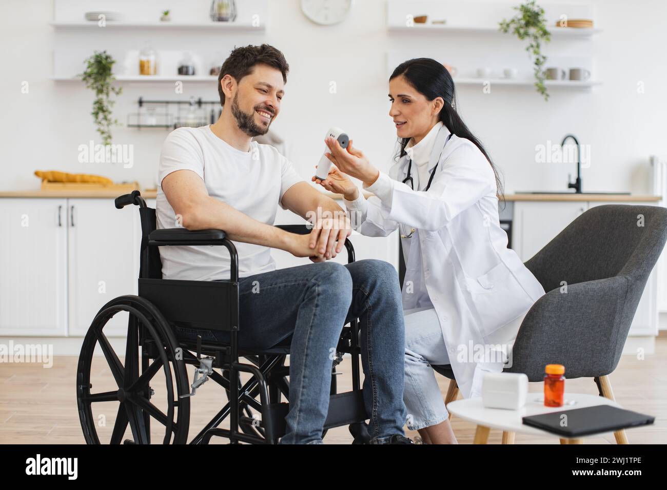 Woman doctor or nurse, visiting her mature male patient with disability ...
