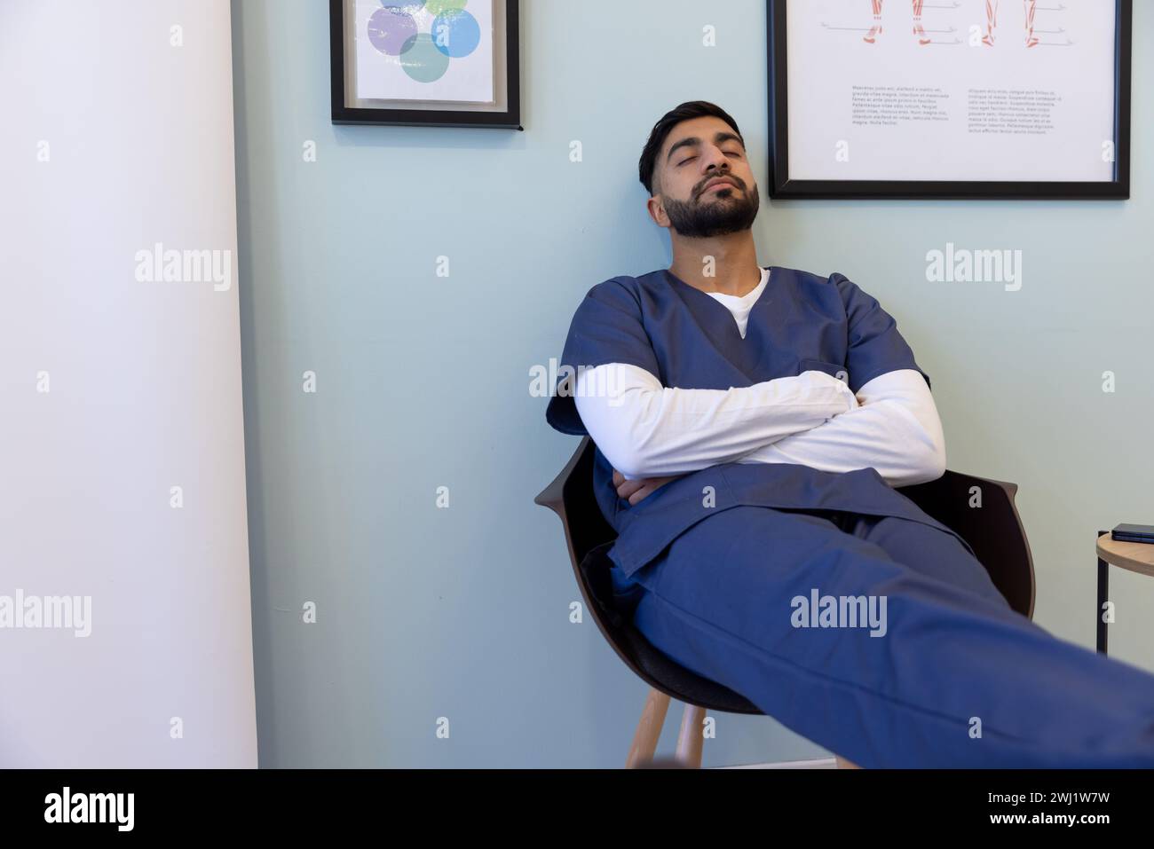 Biracial male doctor taking nap in hospital waiting room Stock Photo ...