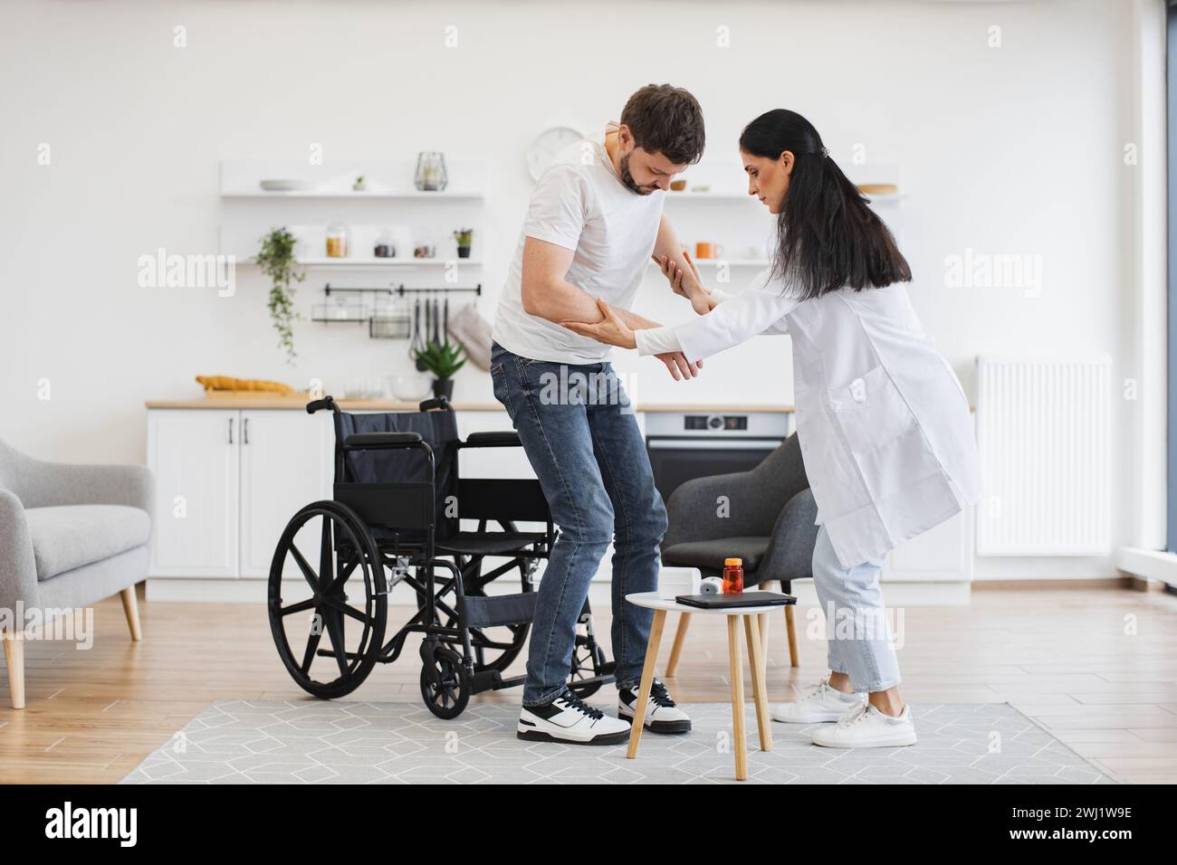 Full length view of man standing near wheelchair while physician giving ...