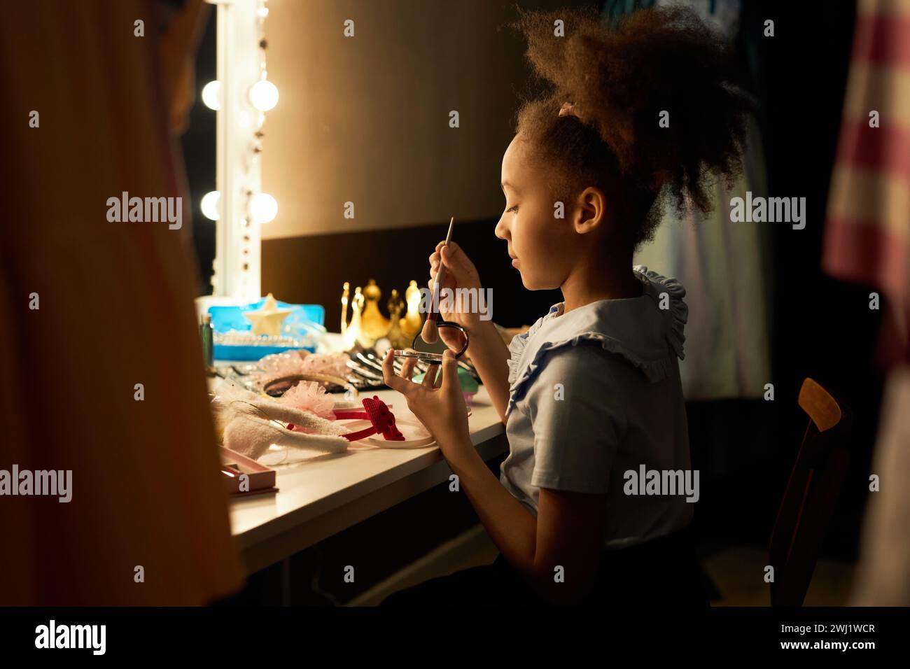 Side view portrait of little Black girl sitting at vanity mirror ...