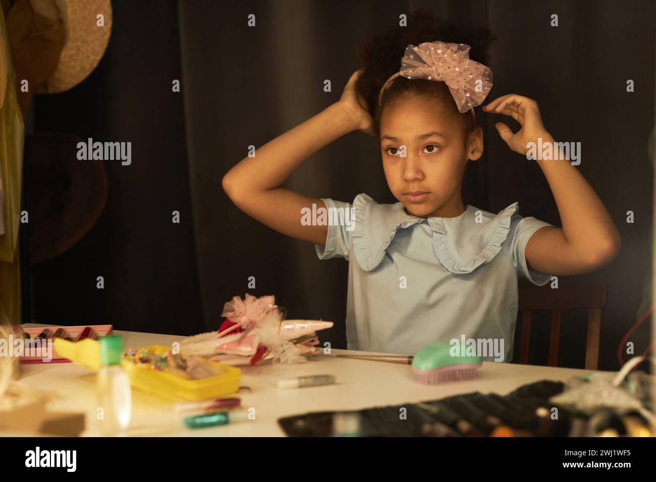 Portrait of young Black girl looking into mirror backstage preparing ...
