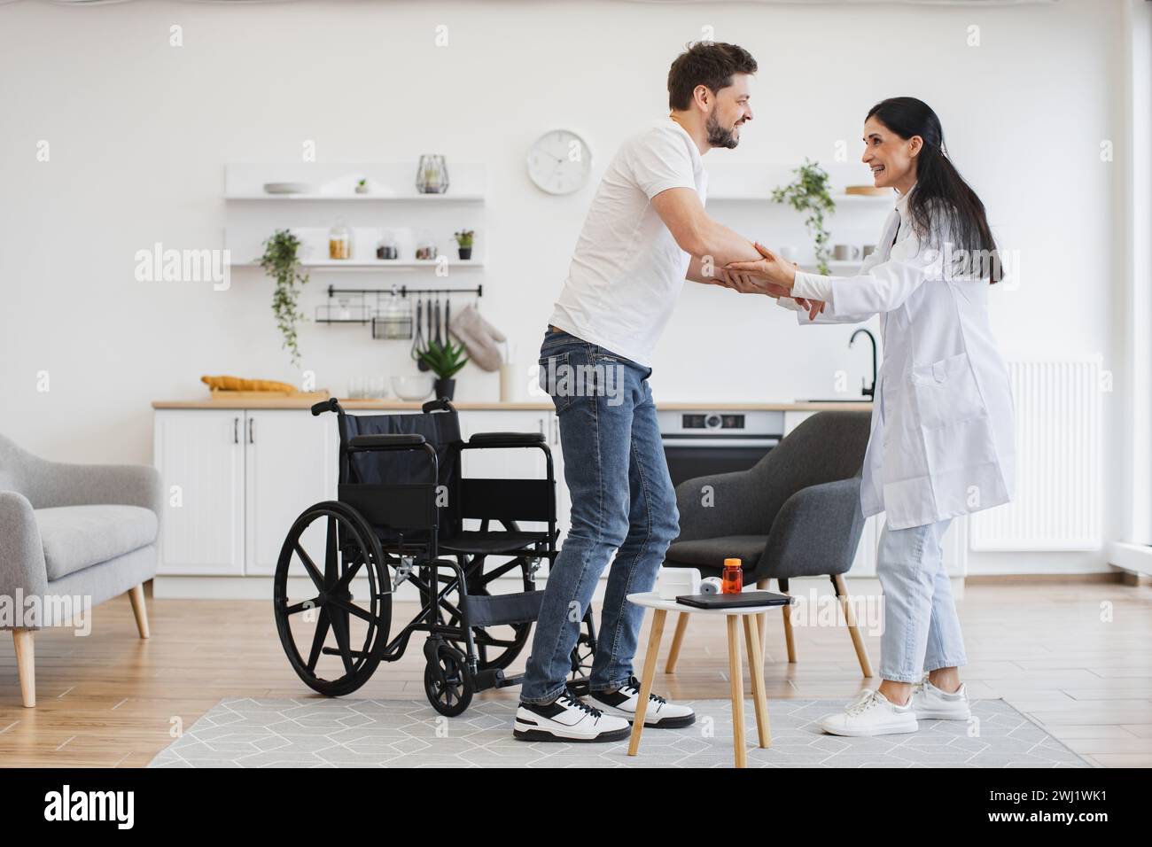 Caucasian woman helping patient with disability to stand from ...